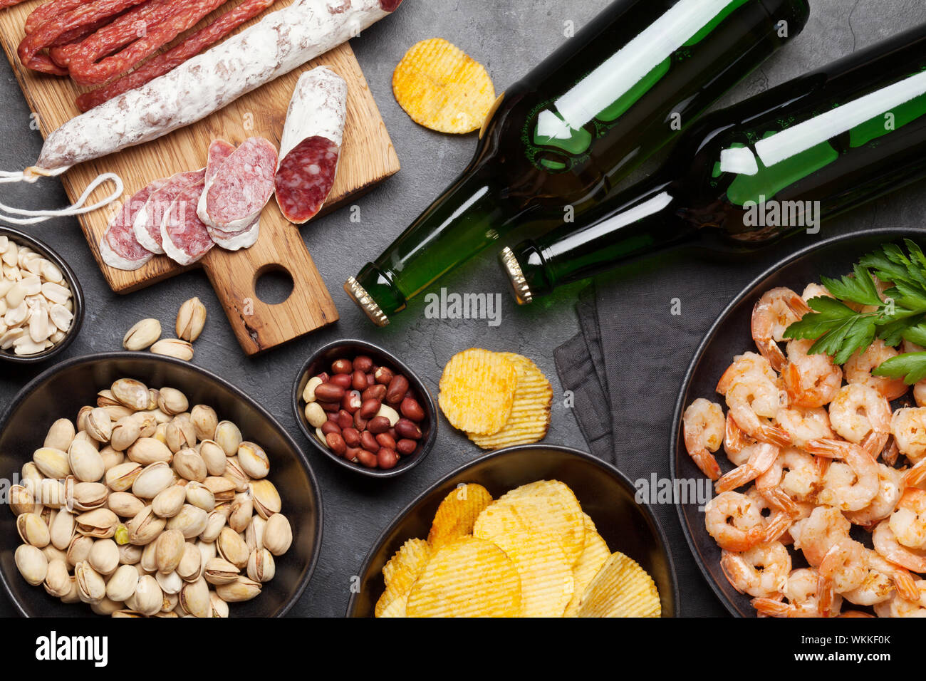 Draft beer and snacks on stone background. Nuts, chips, sausages and ...
