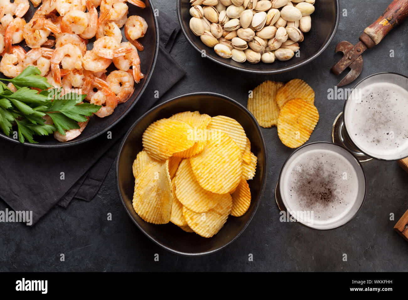 Draft beer and snacks on stone background. Nuts, chips, sausages and ...