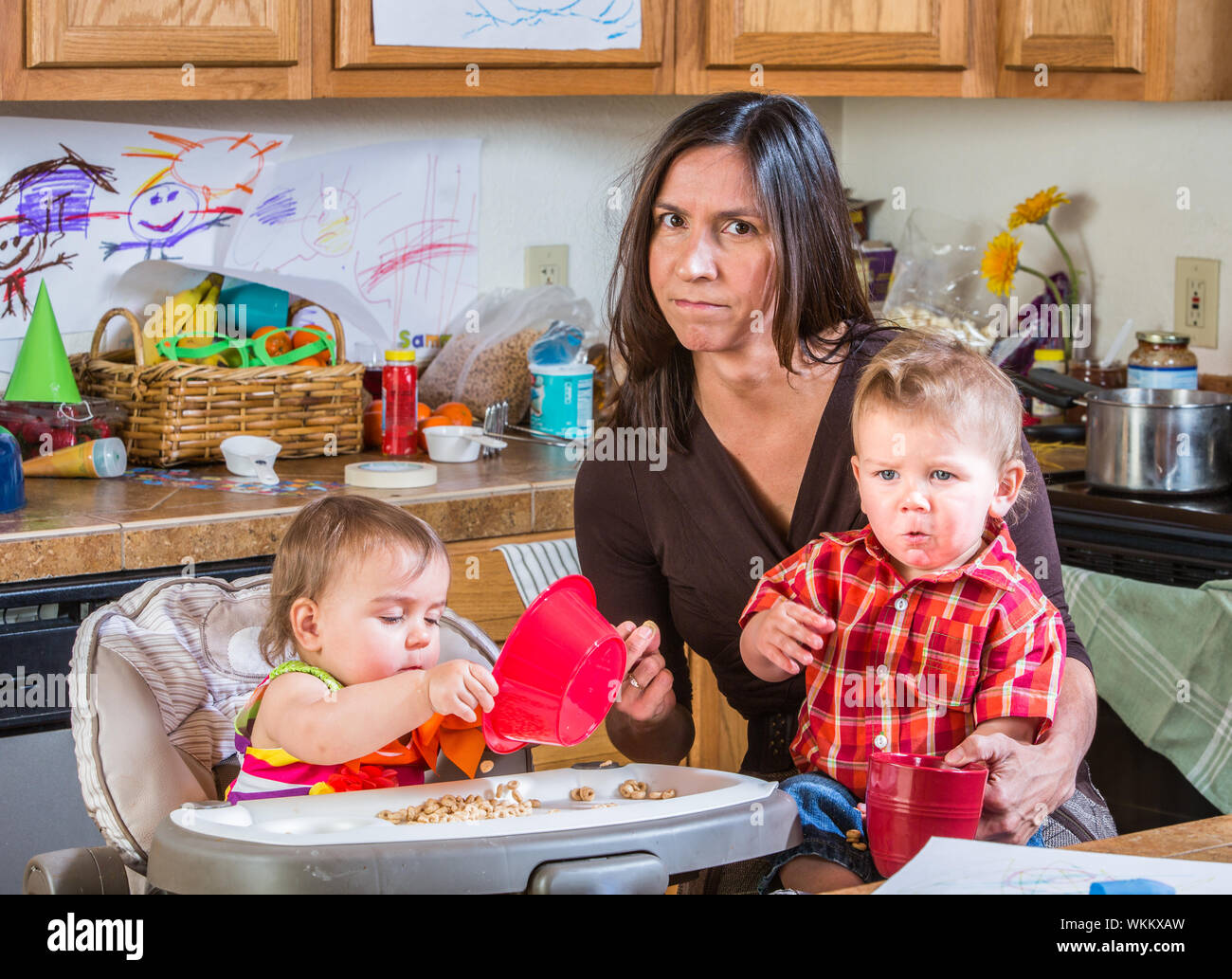 Stressed out mother in kitchen with her babies Stock Photo - Alamy