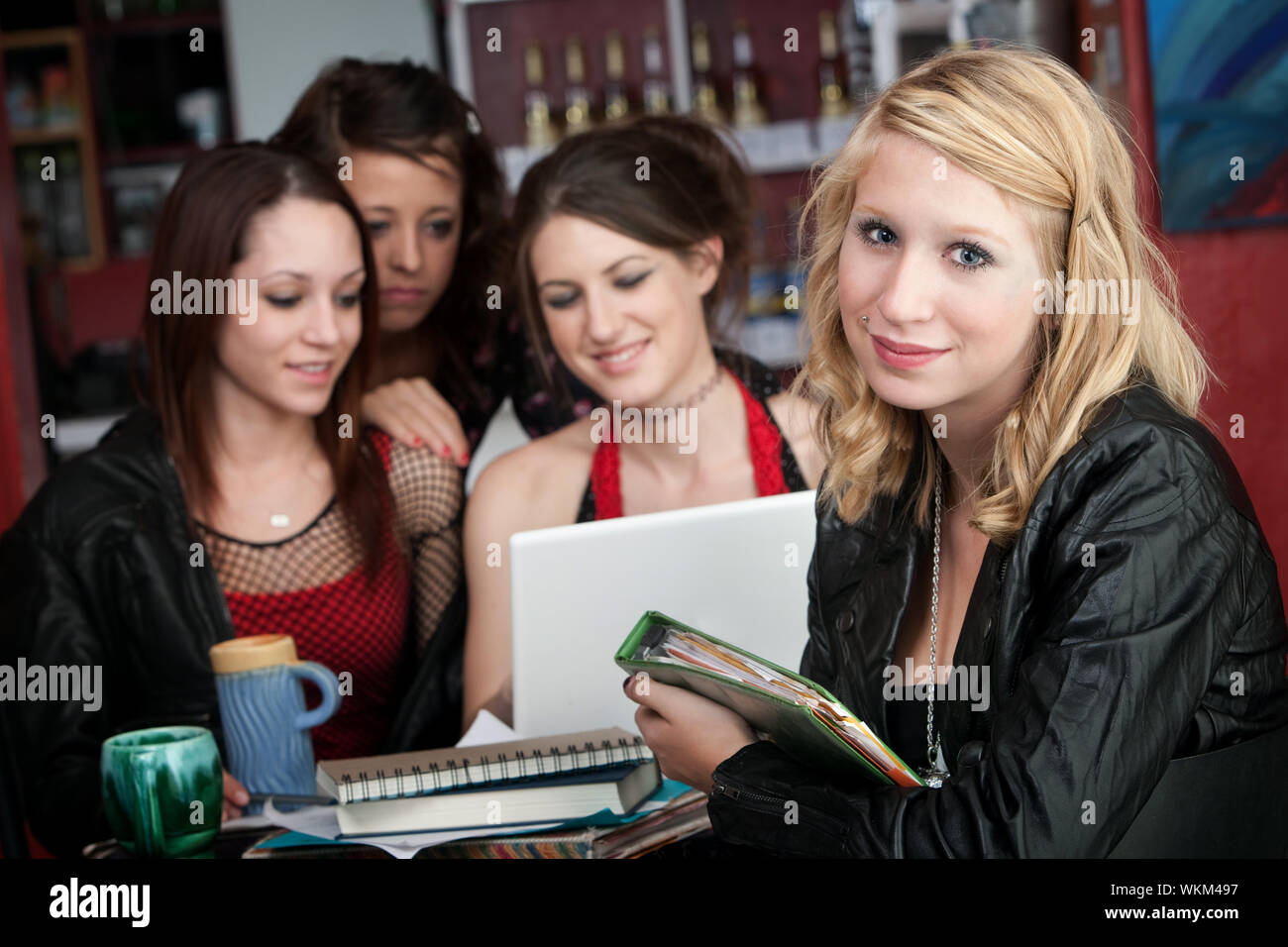 Group of four friends doing their homework in a cafe Stock Photo - Alamy