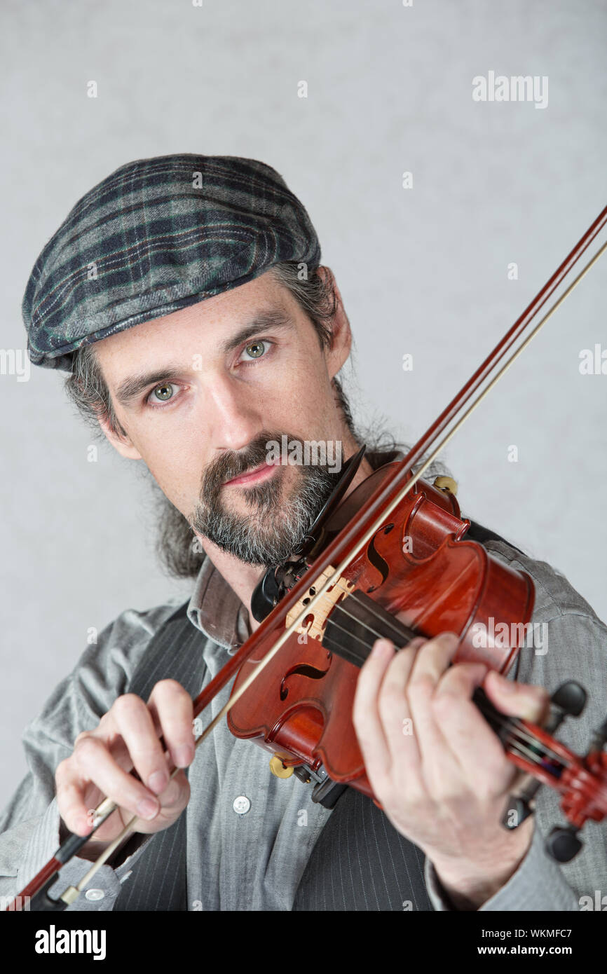 Serious Irish man playing a fiddle over gray background Stock Photo - Alamy