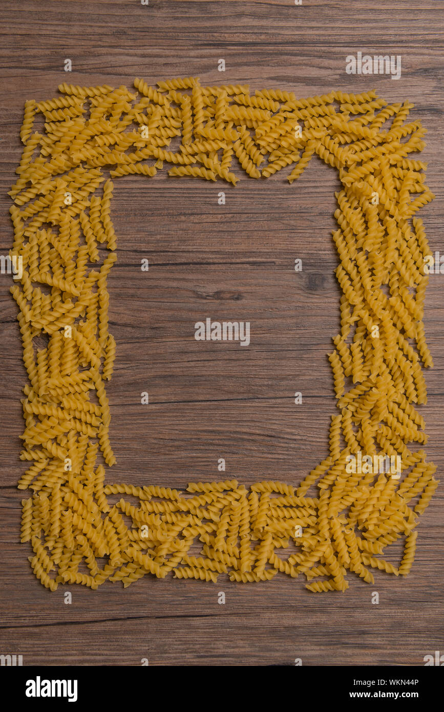 Uncooked italian pasta, brown wood table background Stock Photo - Alamy