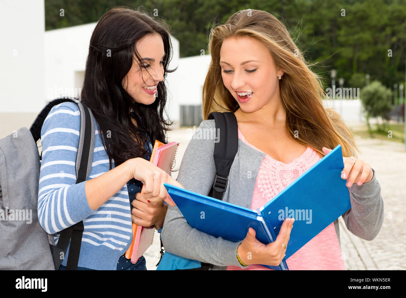 Two beautiful teenage students studying and showing something in the ...