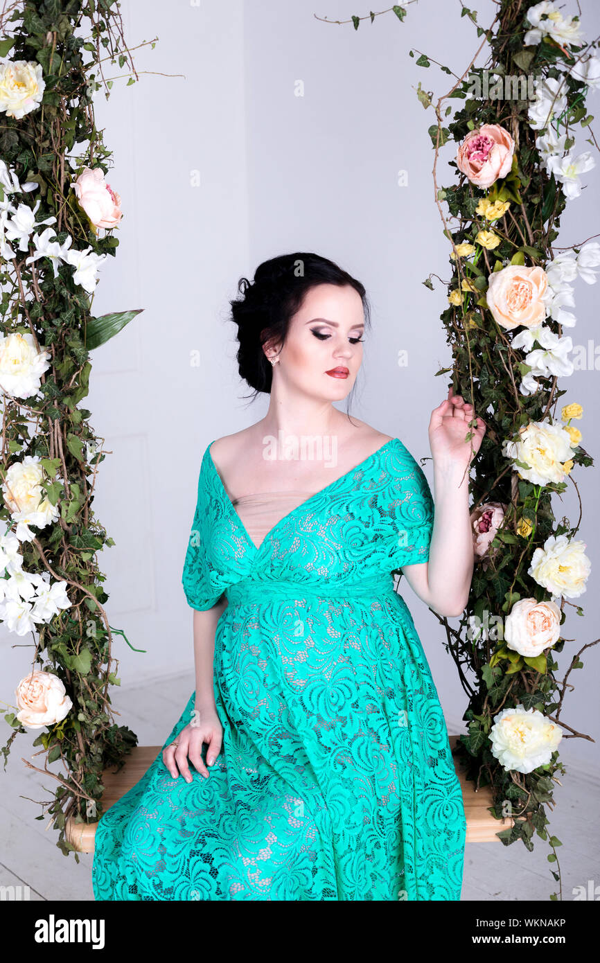 Beautiful pregnant girl in mint dress and a wreath. Studio photography ...