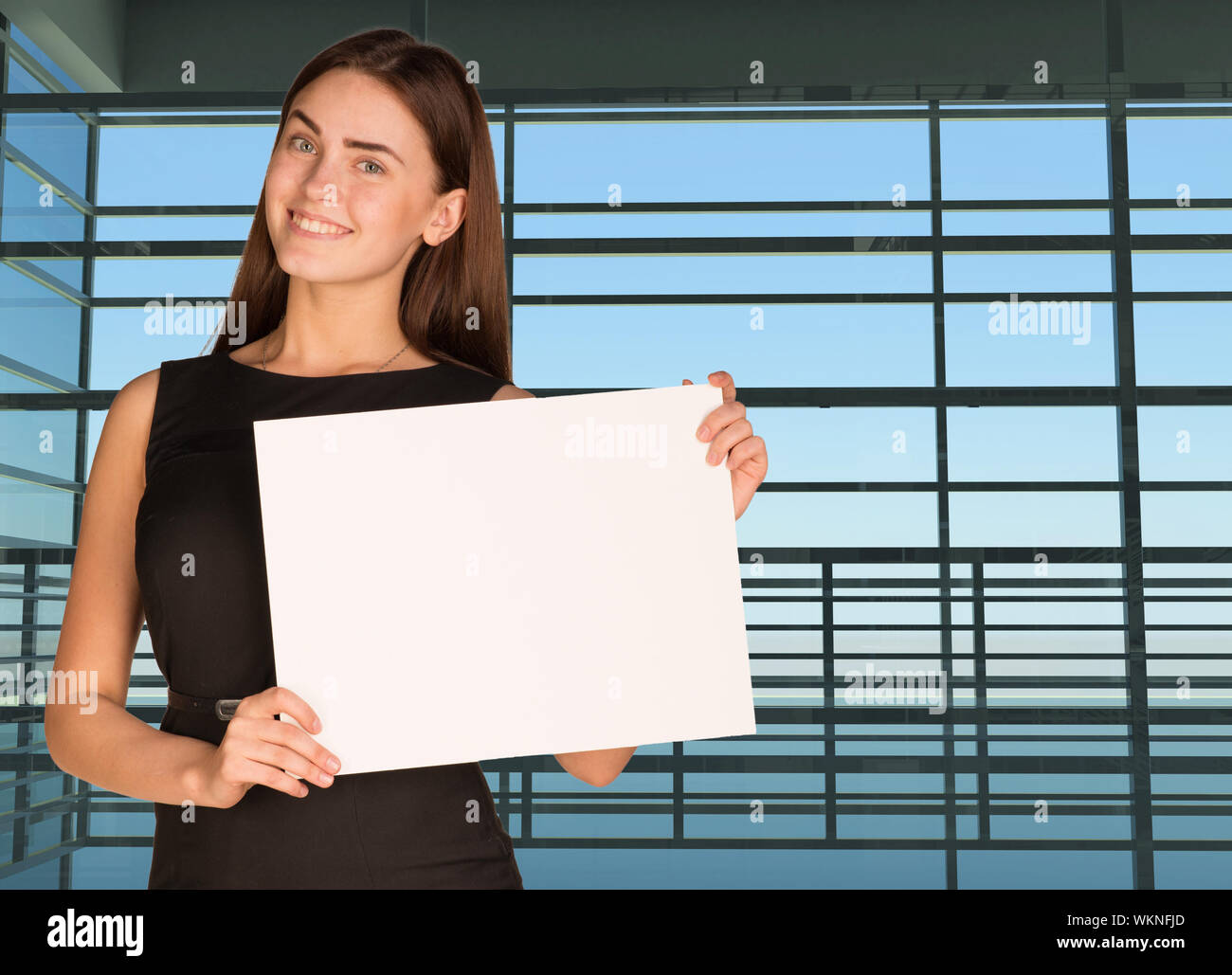 Businesswoman holding paper sheet. Large window as backdrop Stock Photo ...