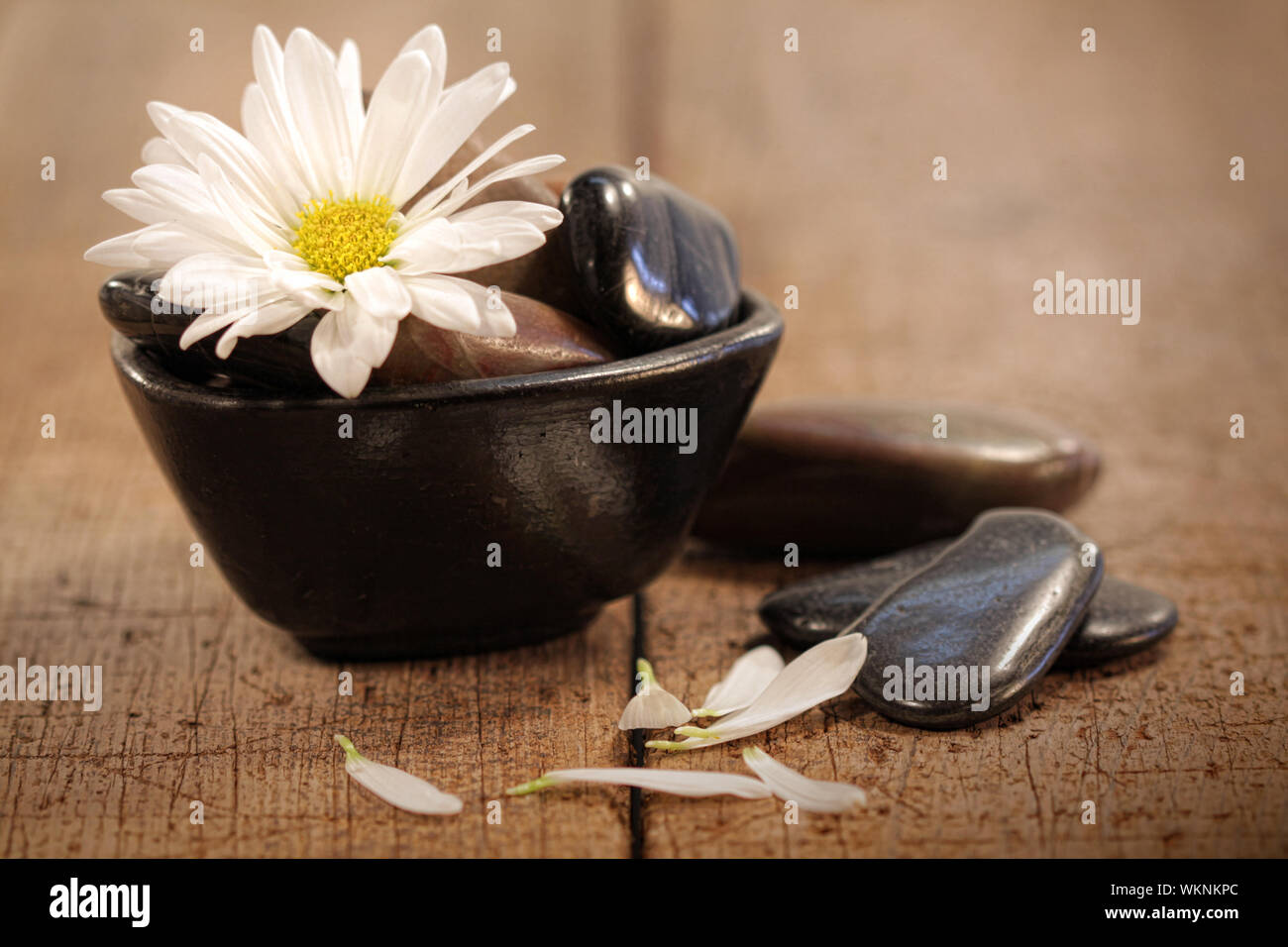 Spa rocks in wooden bowl on rustic wood table Stock Photo - Alamy