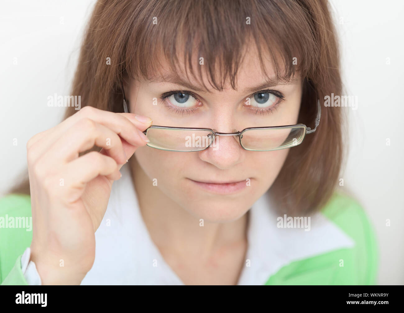 The strict young woman looks at us over eyeglasses Stock Photo - Alamy