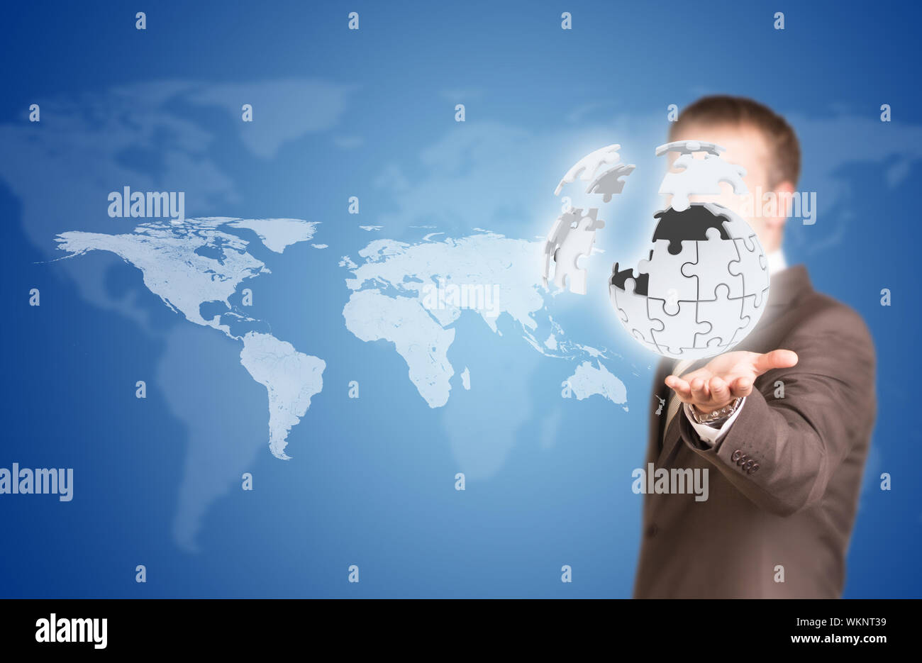 Business man hold exploding ball of gray puzzle pieces in hand. World ...