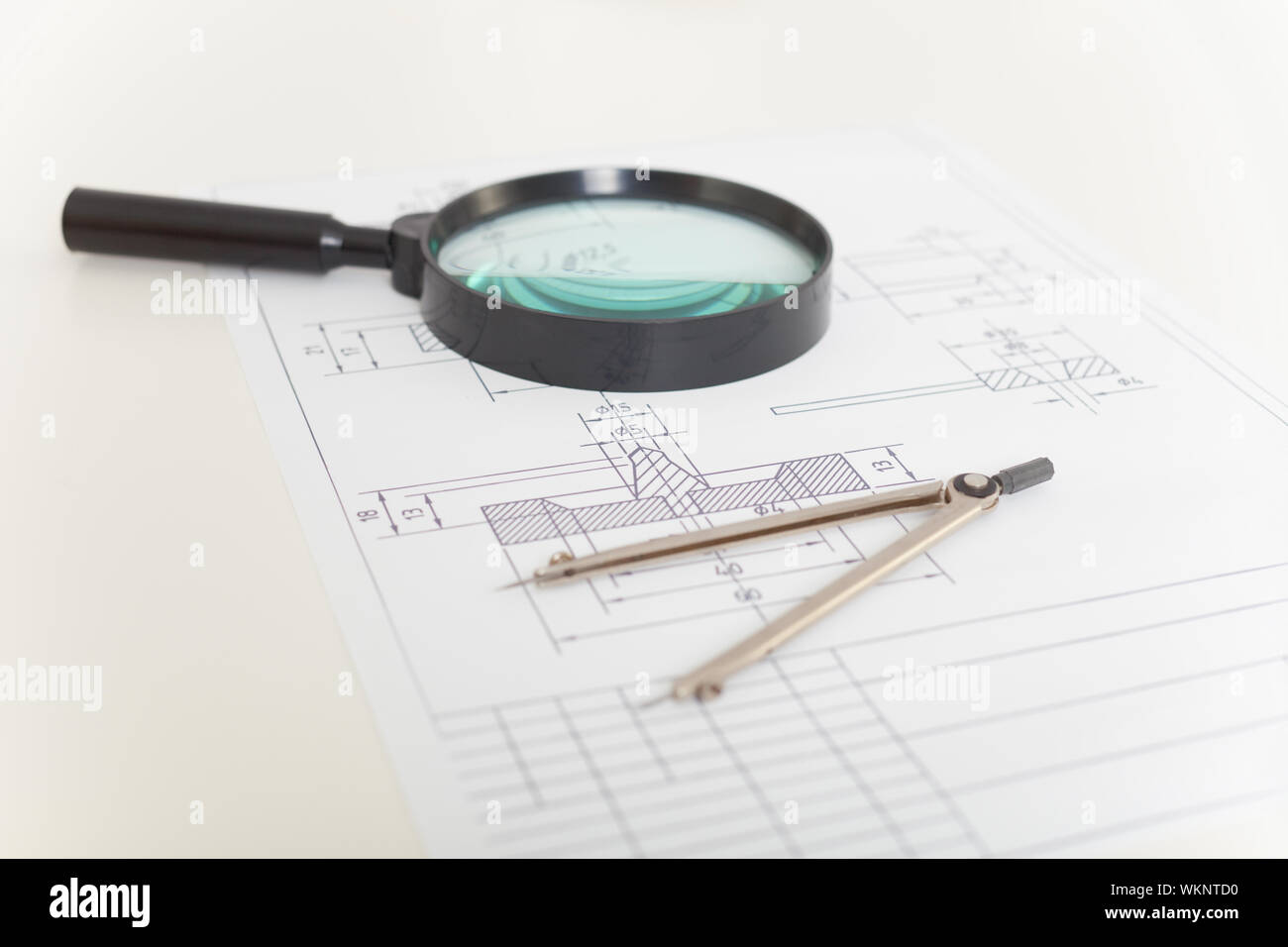The drawings, magnifier and compasses on a white table Stock Photo - Alamy
