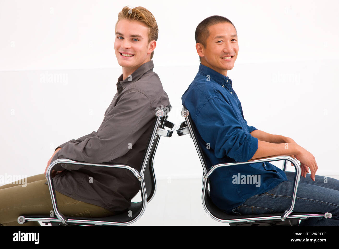 Two businessman sitting in chairs to back Stock Photo - Alamy