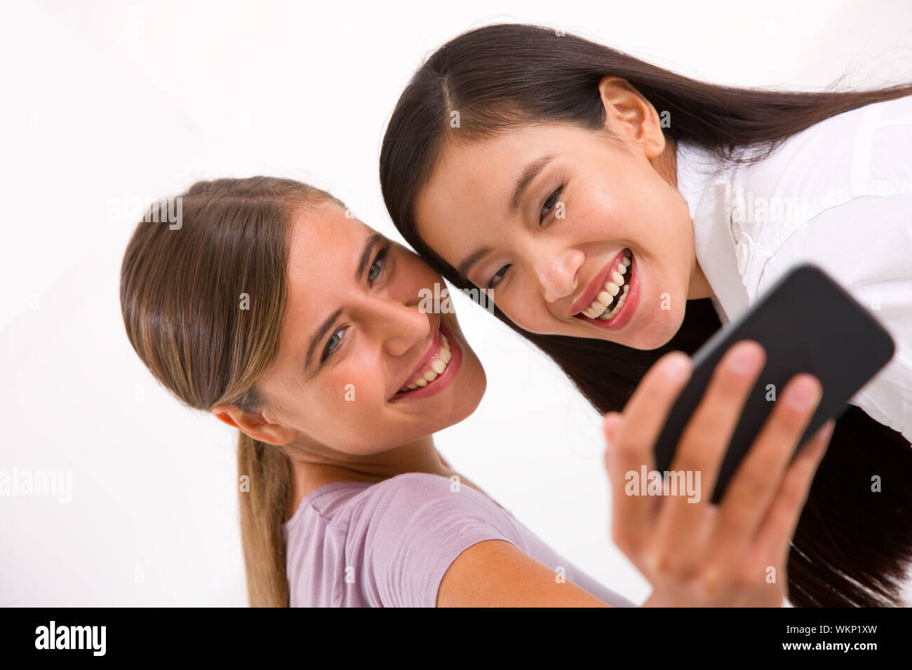 Two smiling young women taking self portrait with cell phone Stock ...