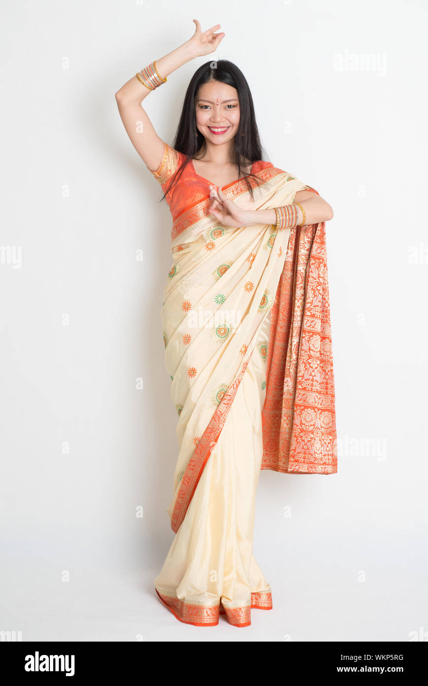 Full length Asian Indian female in dancing pose on plain background ...