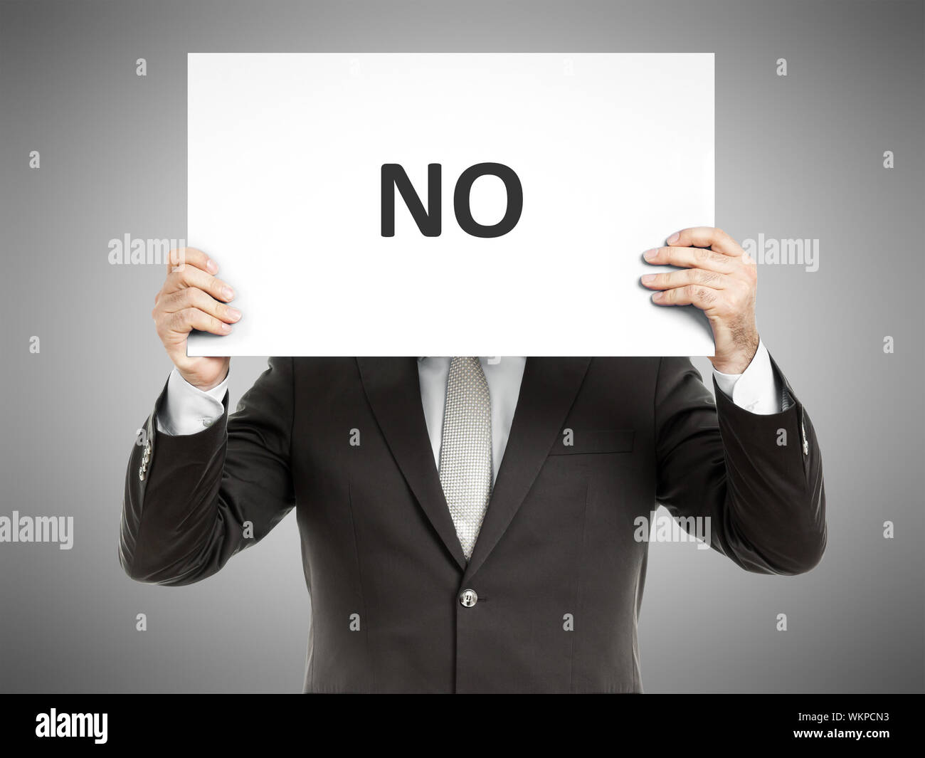 A business man holding a paper in front of his face with the word no ...
