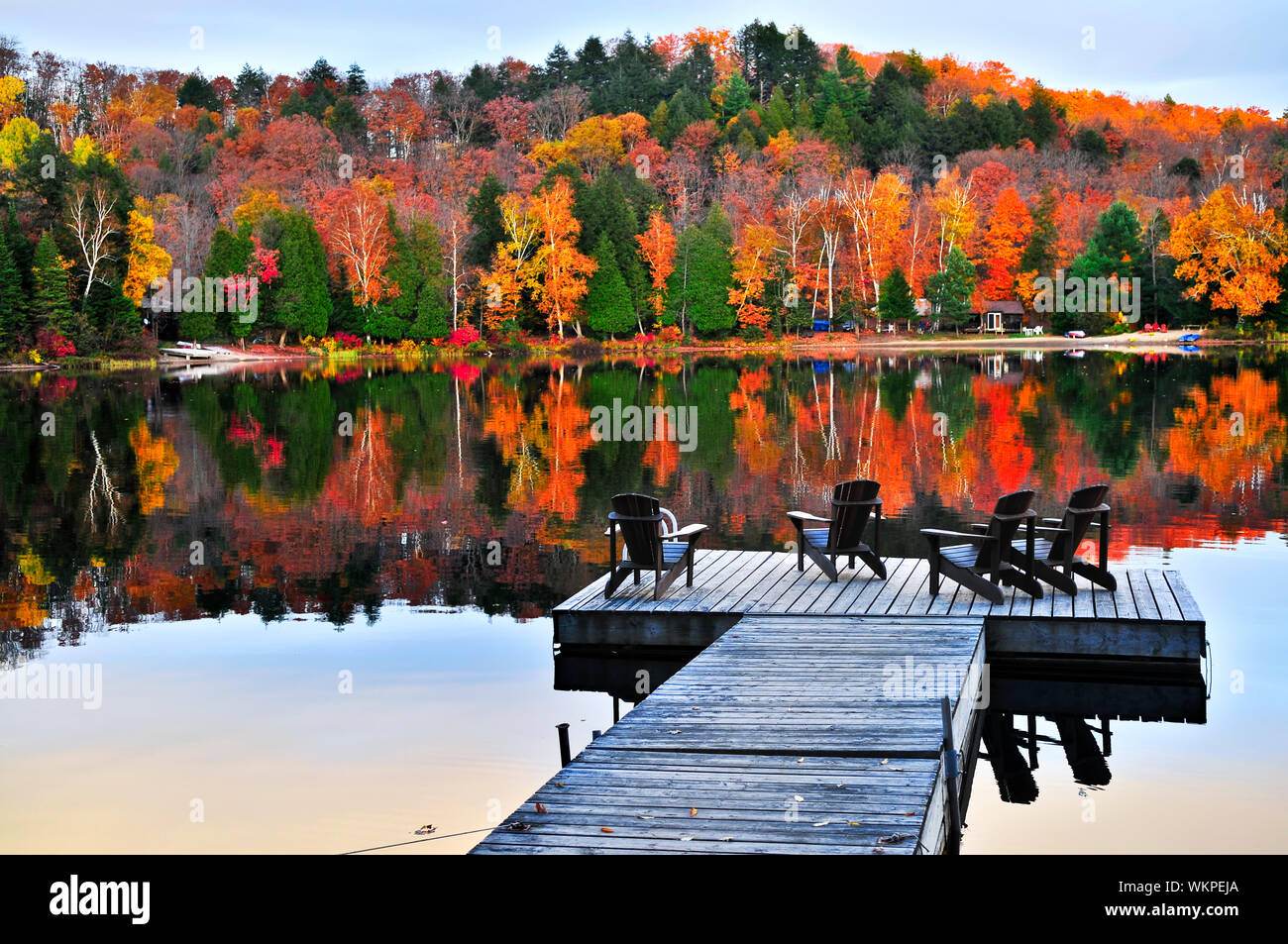 Wooden dock with chairs on calm fall lake Stock Photo - Alamy