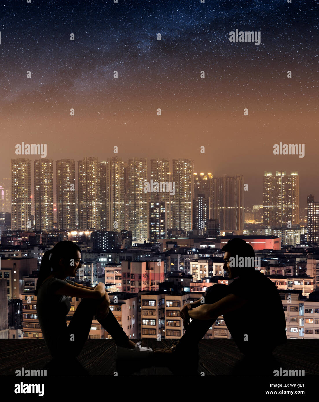 Silhouette of young couple face to face sit on ground in the city night ...