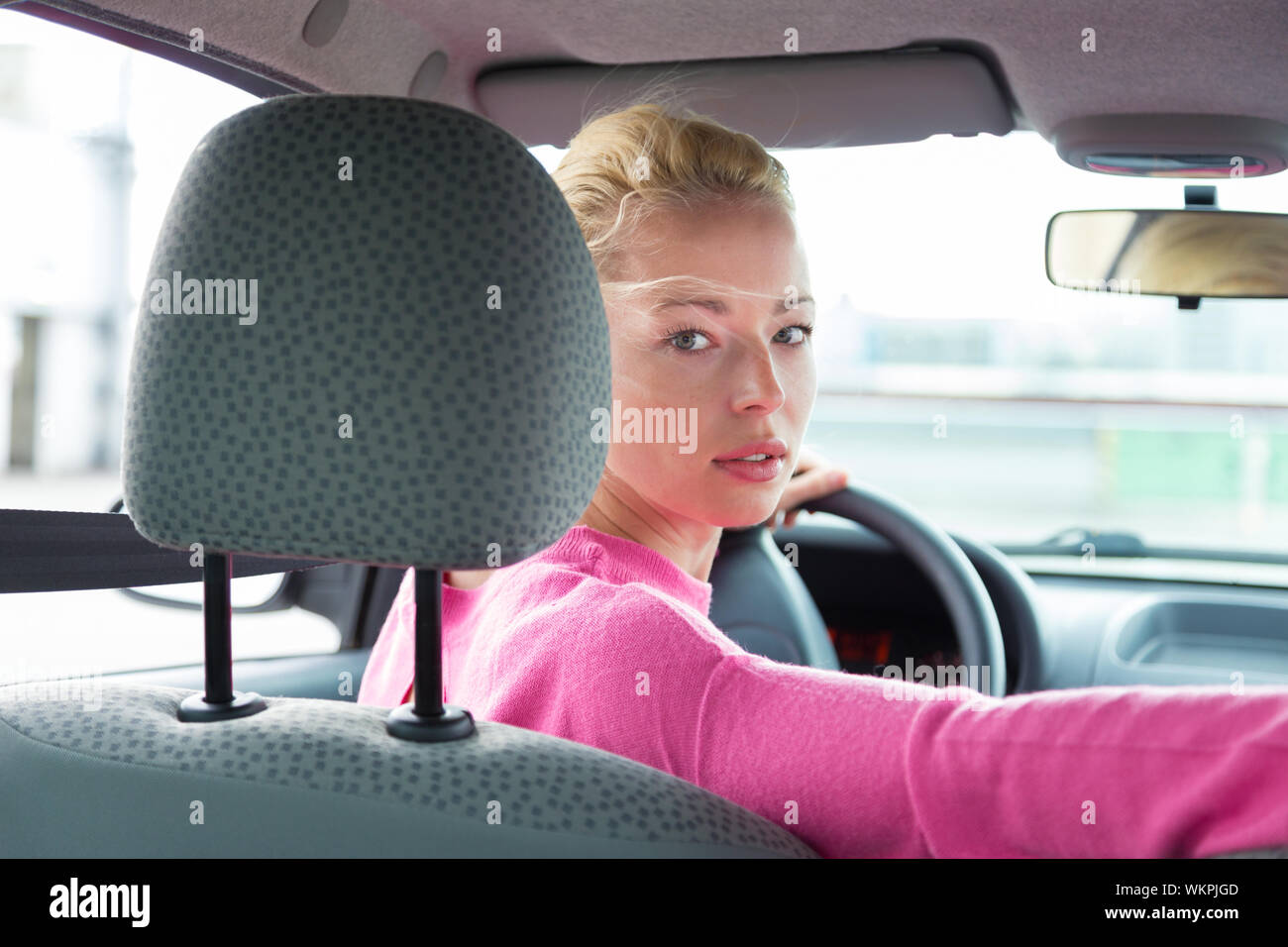 Beautiful young lady looking back through the rear window from the ...
