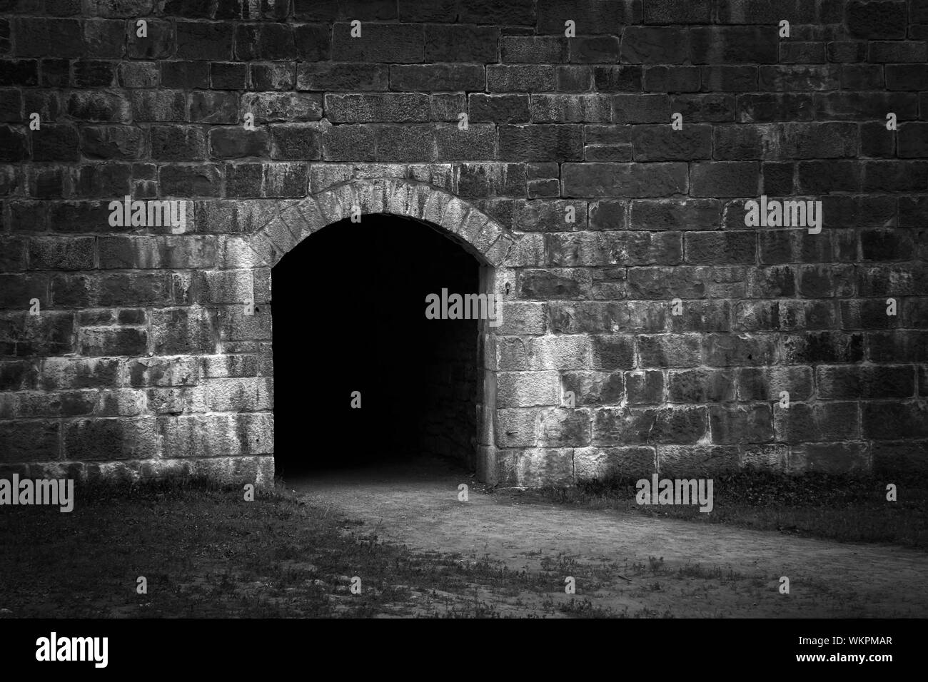 Dark and scary passage way in old stone wall, in black and white Stock ...