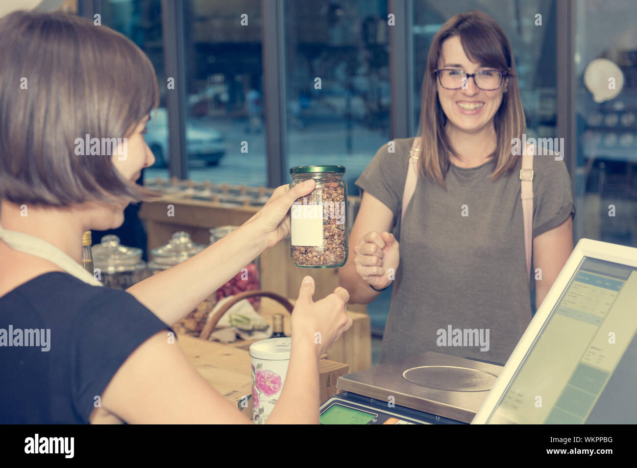Female shop assistant serving a customer at a desk Stock Photo - Alamy