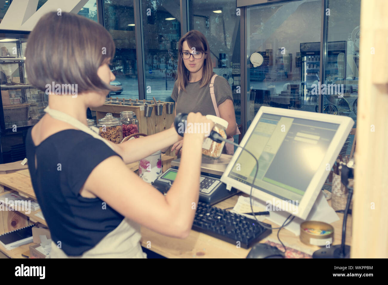Female shop assistant serving a customer at a desk Stock Photo - Alamy