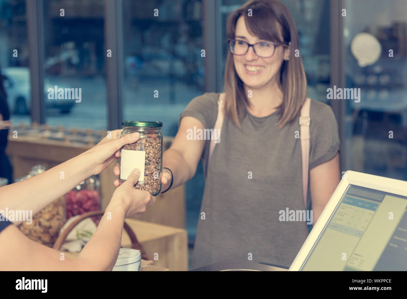 Female shop assistant serving a customer at a desk Stock Photo - Alamy