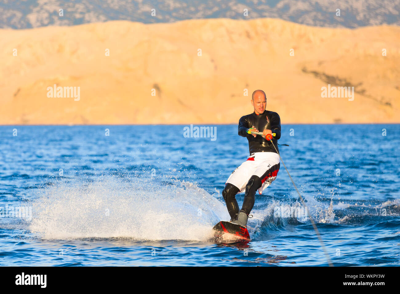 Wakeboarder in wetsuit riding in sunset. Wakeboarding is a surface ...