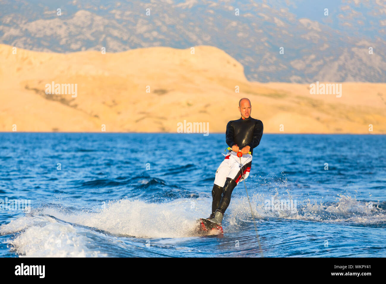 Wakeboarder in wetsuit riding in sunset. Wakeboarding is a surface ...