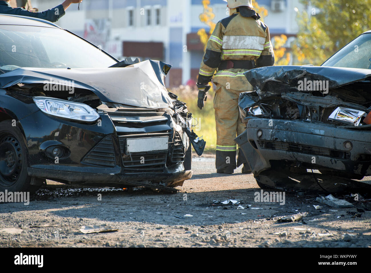 two cars with broken and deformed front parts and a man standing with ...