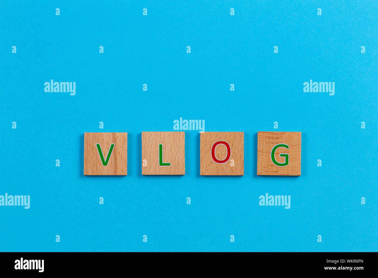 The word VLOG, spelt with wooden letter tiles over blue background. Top ...