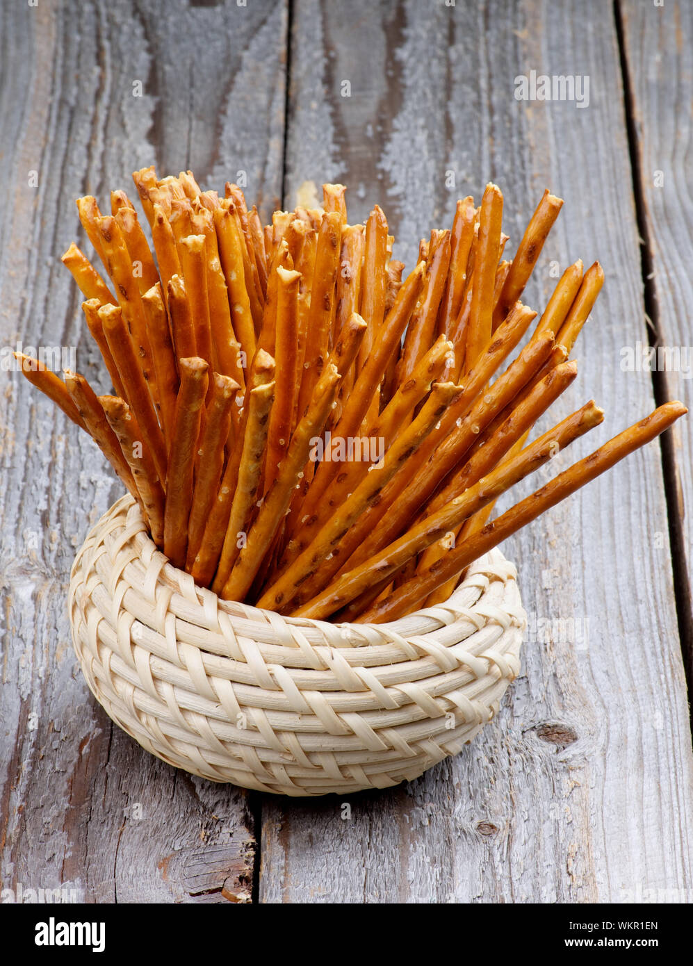 Bunch of Pretzel Rods Sticks in Wicker Bowl isolated on Rustic Wooden ...