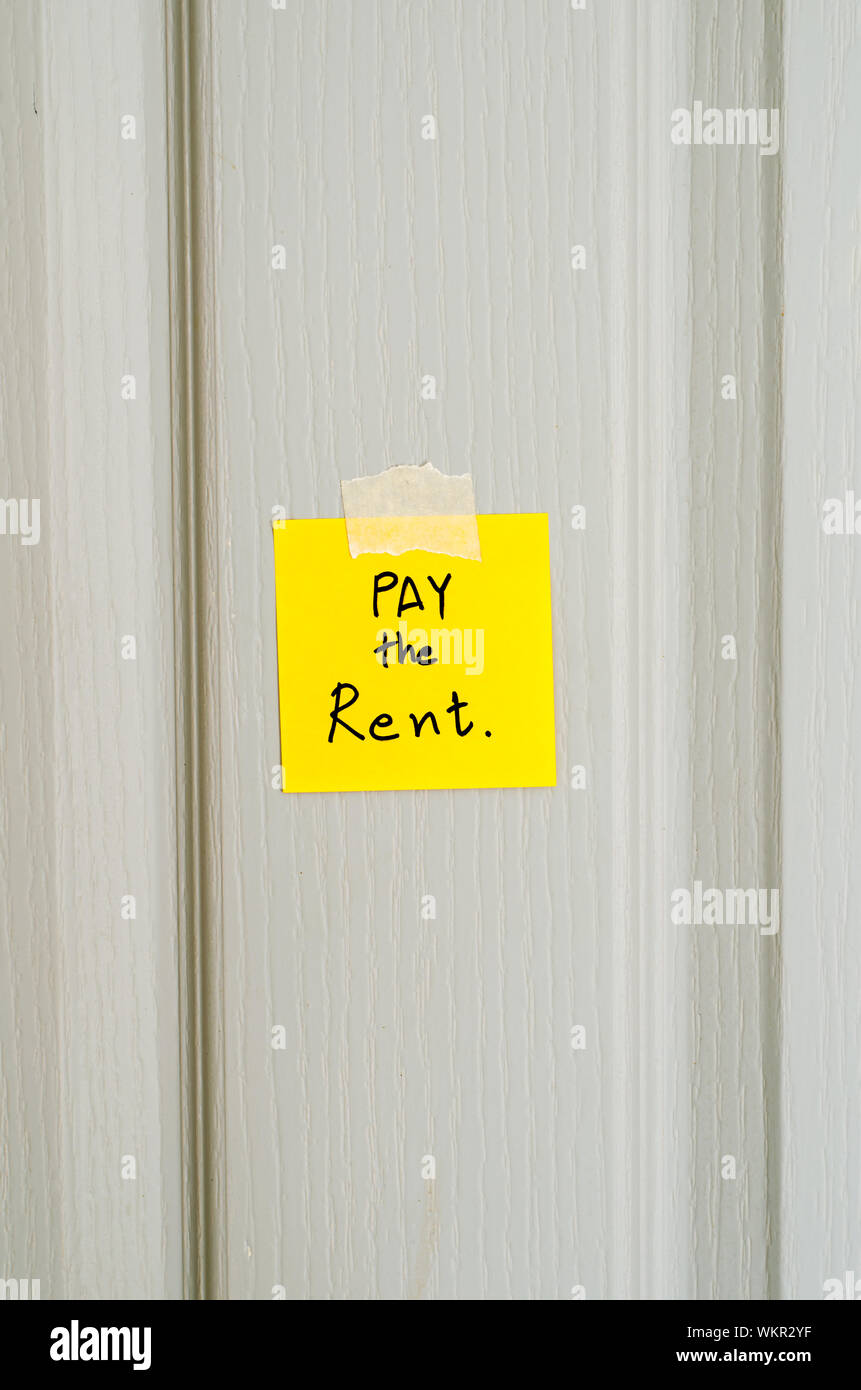 sticky note write a message pay the rent on wood door background Stock ...