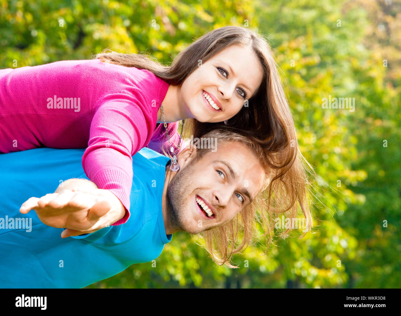 happy young couple piggybacking, arms outstretched, smiling Stock Photo ...