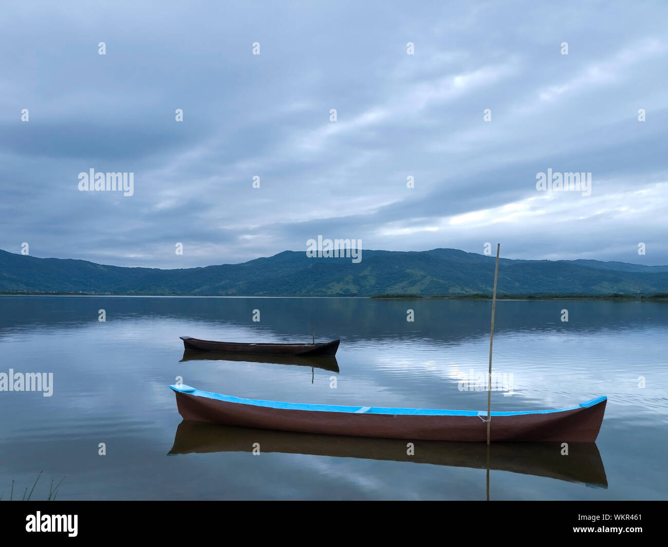 Two canoes tied on a quiet lake under a cloudy sky Stock Photo - Alamy