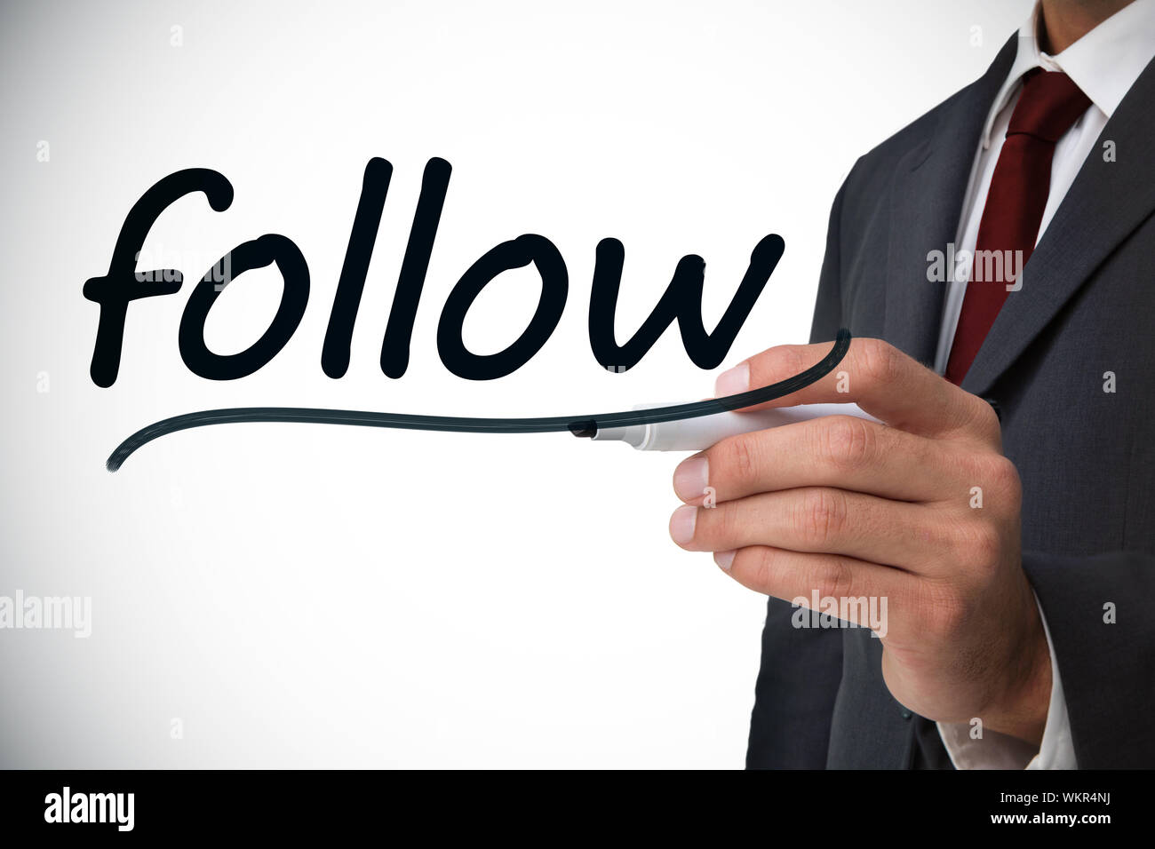 Businessman writing the word follow against white background with ...
