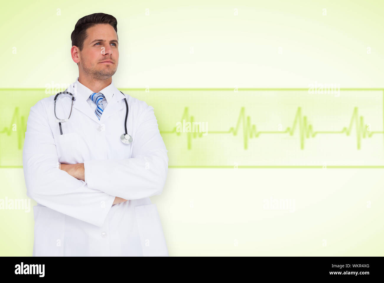 Handsome doctor with arms crossed against medical background with green ...