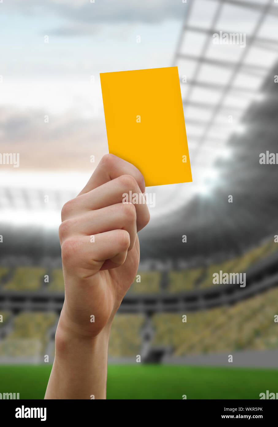Hand holding up yellow card against football stadium Stock Photo - Alamy