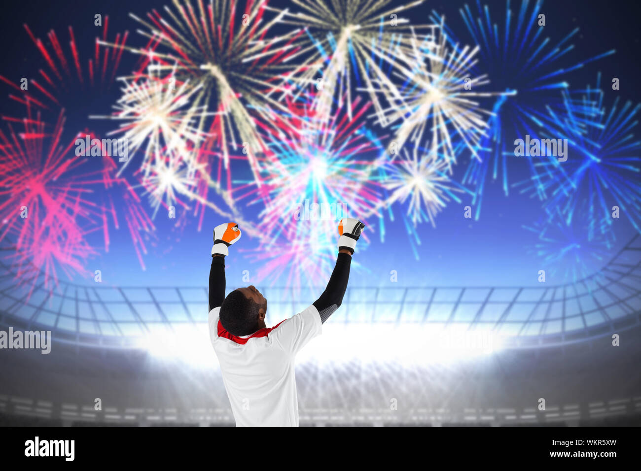 Excited goalkeeper in white cheering against fireworks exploding over ...