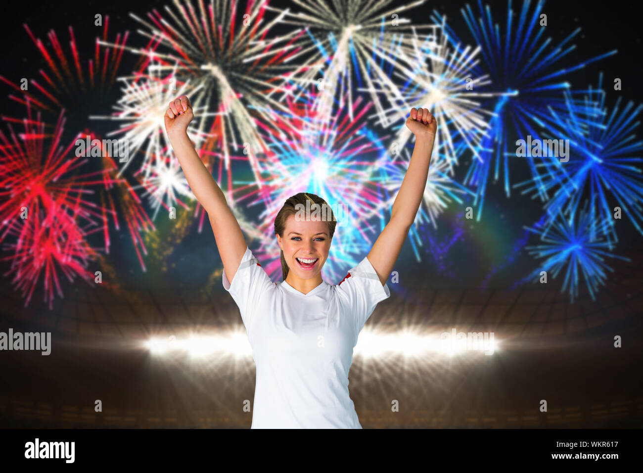 Pretty football fan in white cheering against fireworks exploding over ...