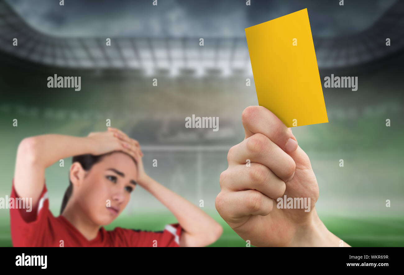 Composite image of hand holding up yellow card to fan against football ...