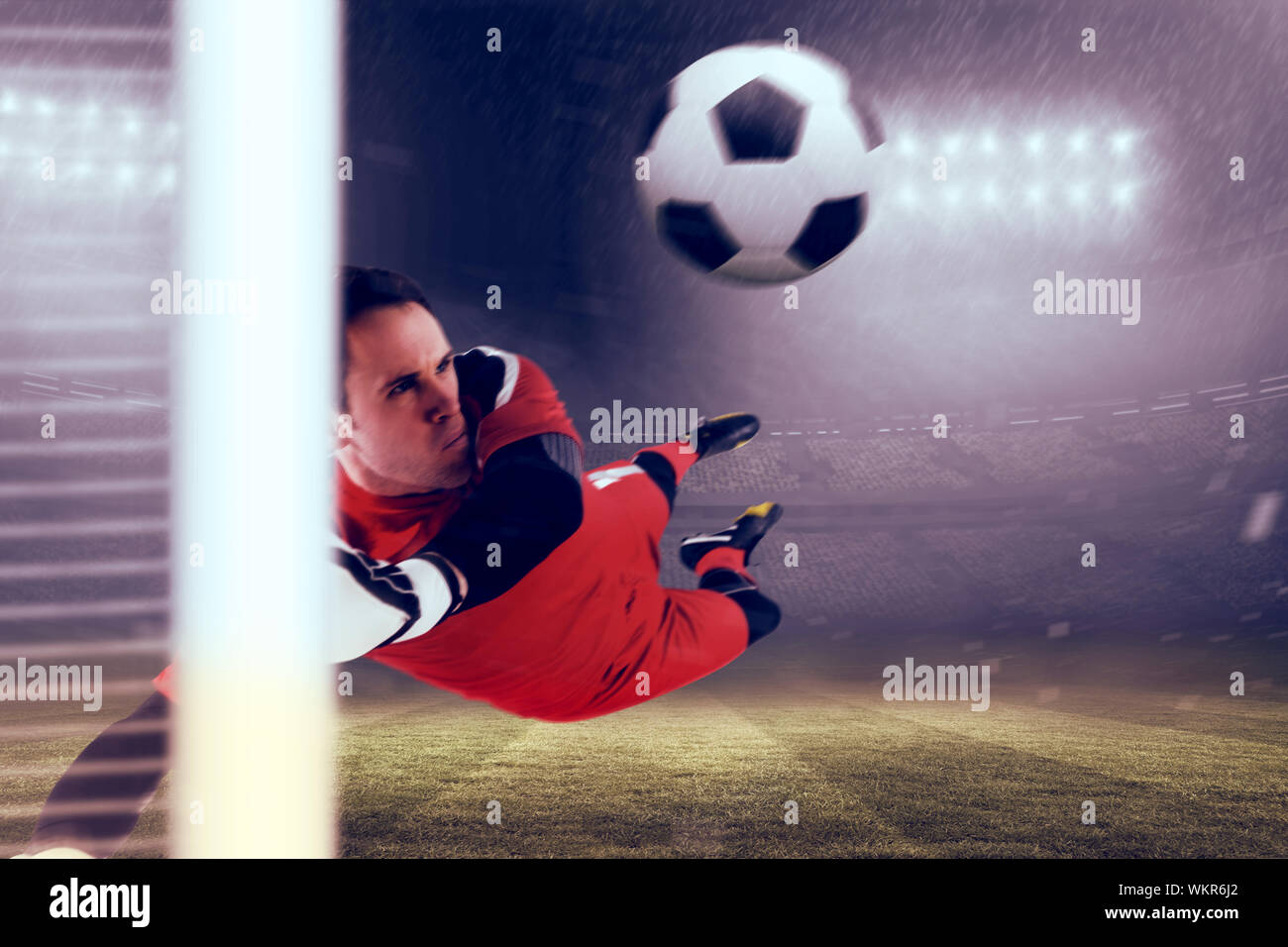 Fit goal keeper jumping up against large football stadium under blue ...