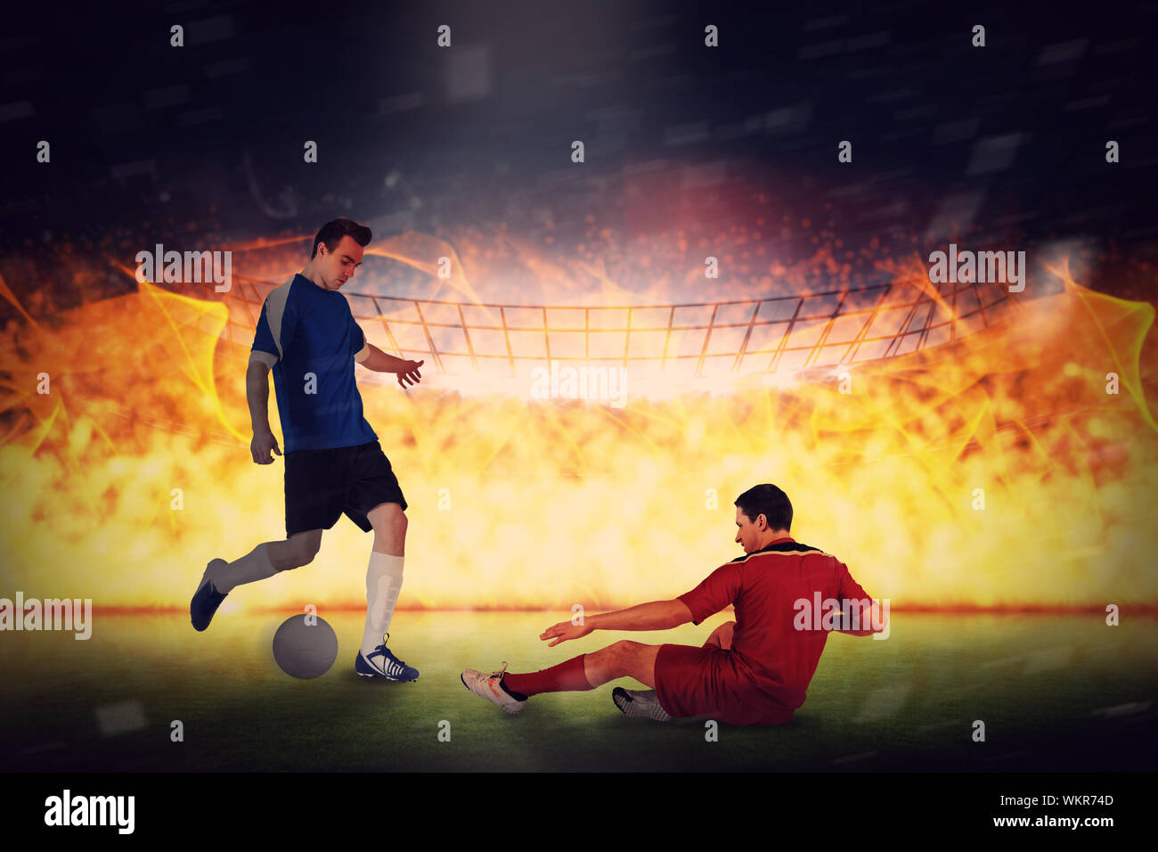 Football players tackling for the ball against large football stadium ...