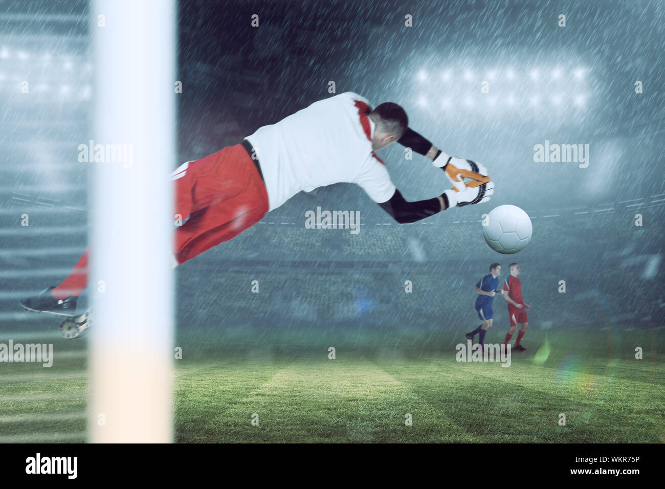 Fit goal keeper jumping up against large football stadium under blue ...