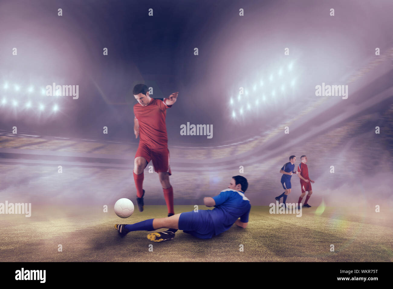Football players tackling for the ball against football stadium Stock ...