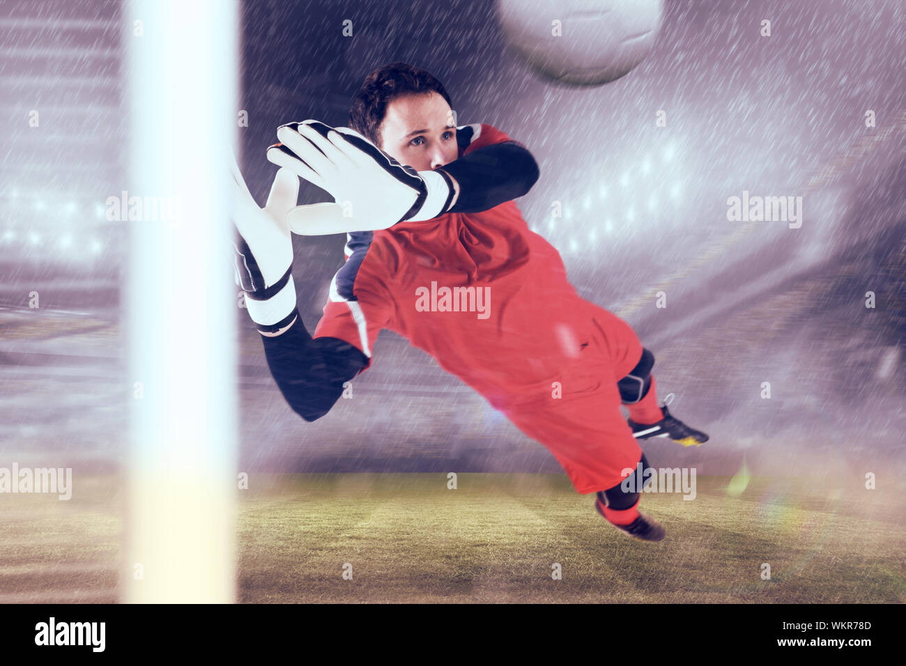 Fit goal keeper jumping up against football stadium Stock Photo - Alamy