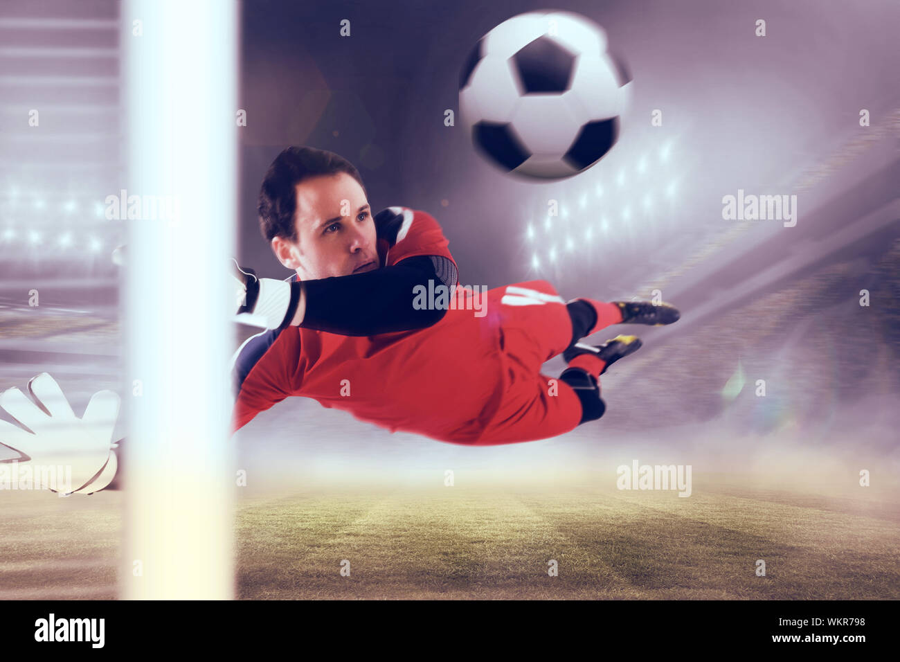Fit goal keeper jumping up against football stadium Stock Photo - Alamy