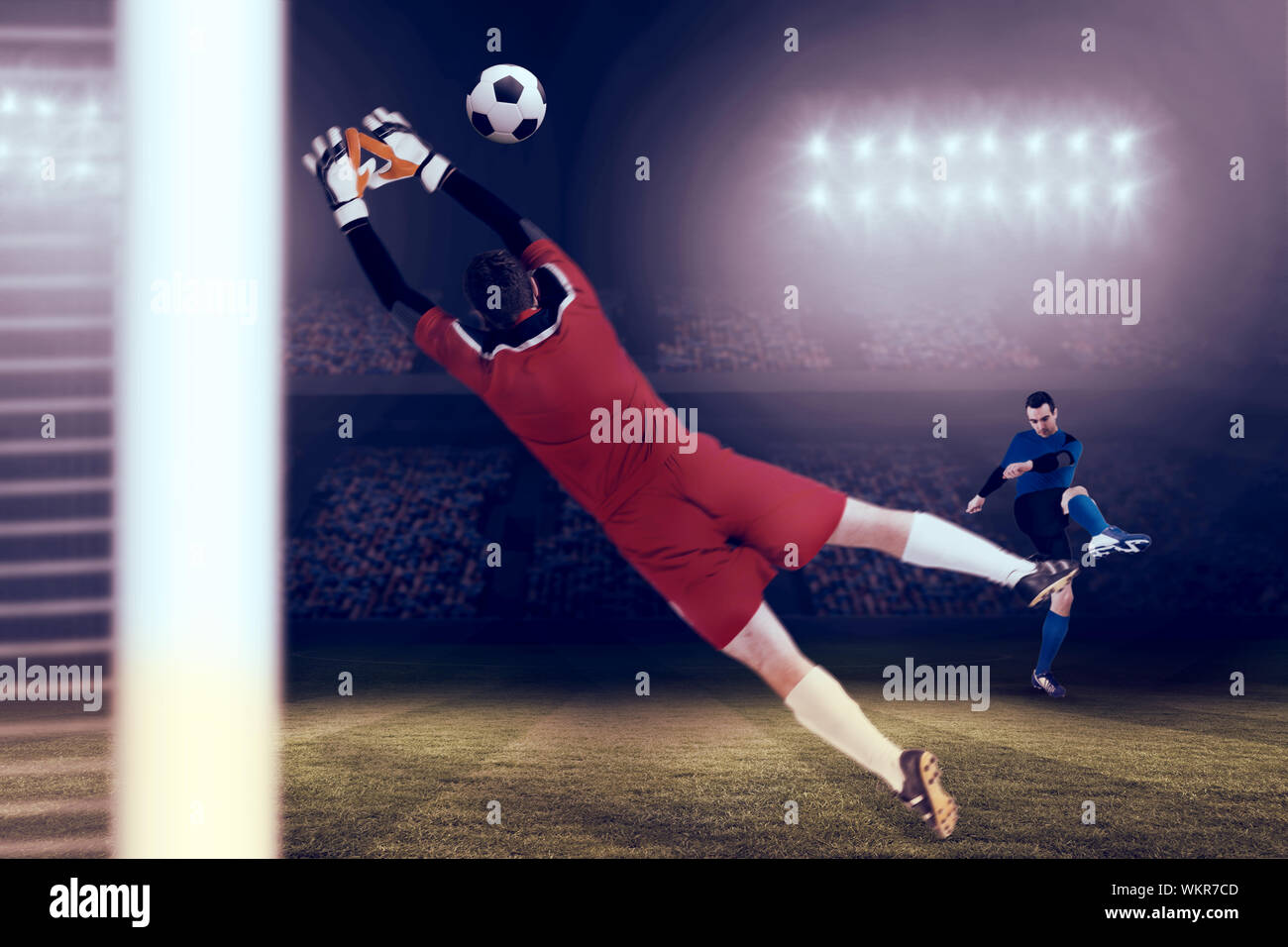 Goalkeeper in red jumping up against large football stadium under blue ...