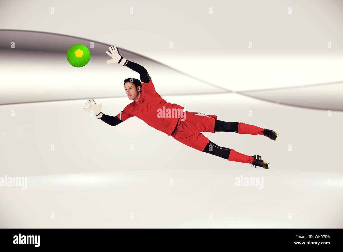 Fit goal keeper jumping up against futuristic bright grey background ...