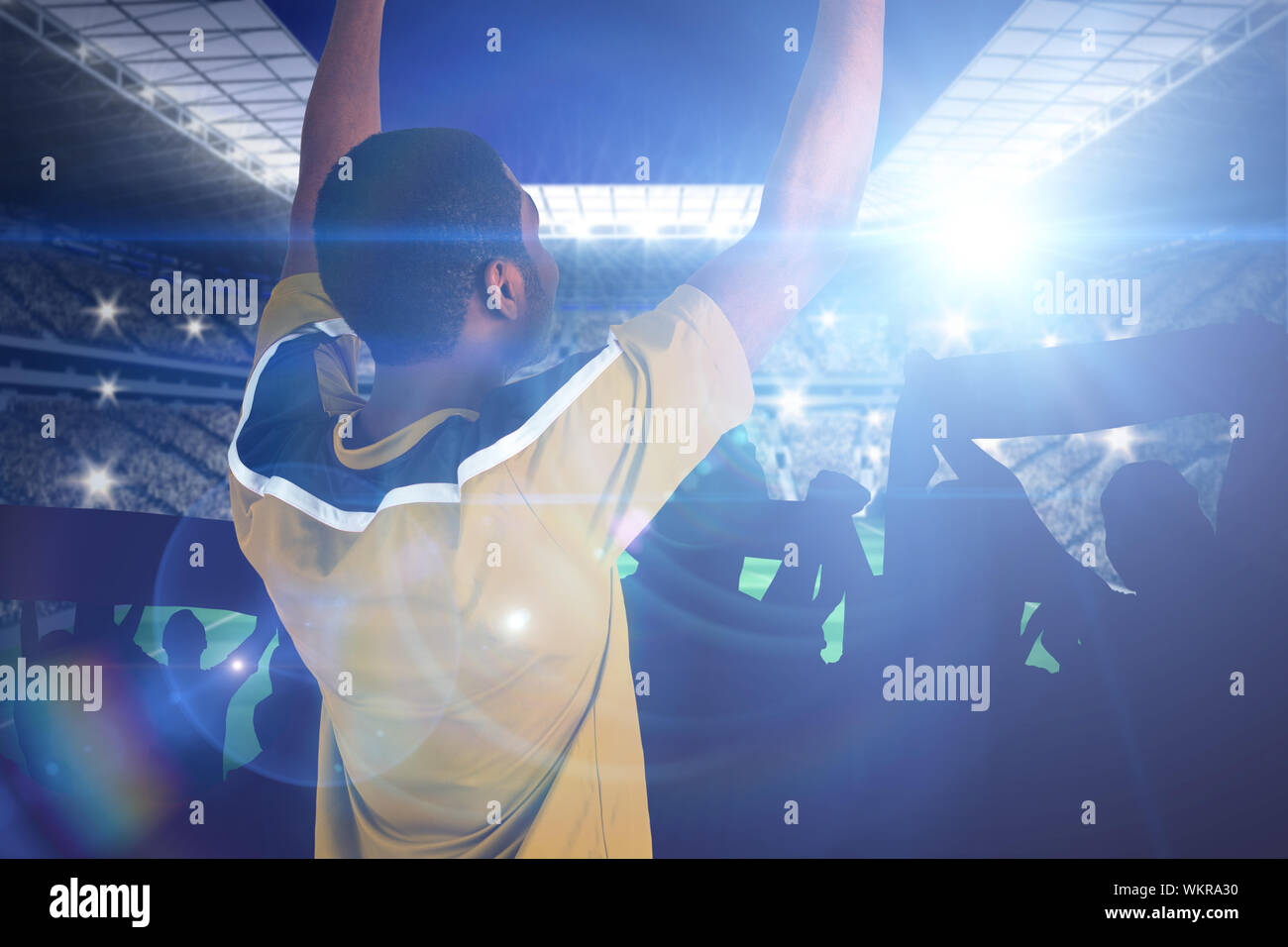 Cheering football fan in yellow jersey against large football stadium ...