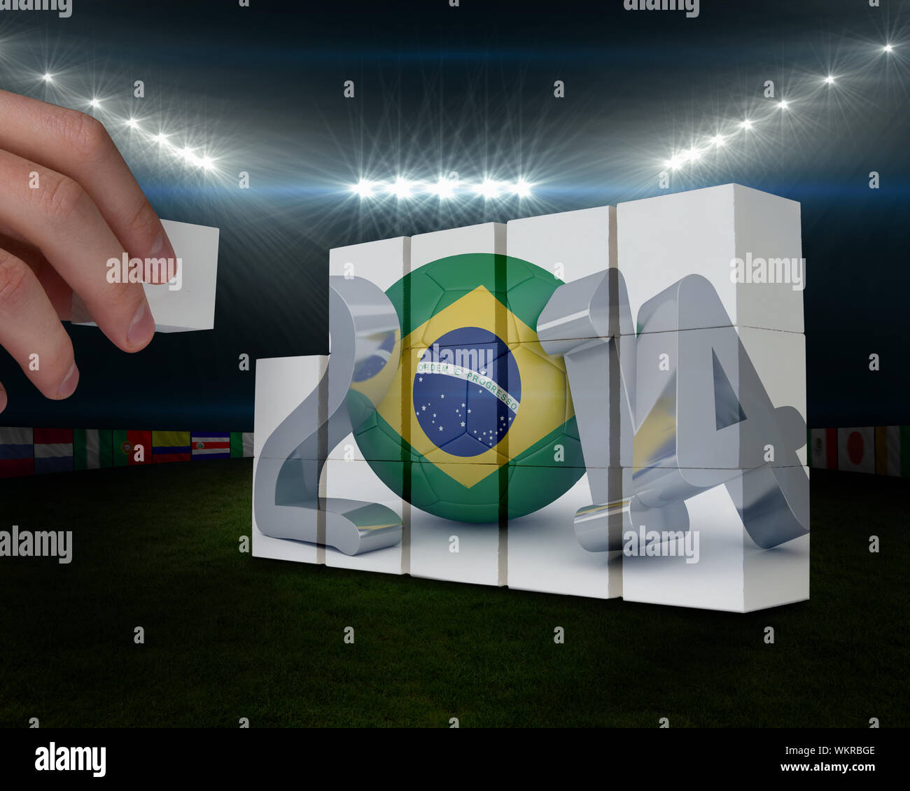 Hand building wall against football pitch with flags and lights Stock ...