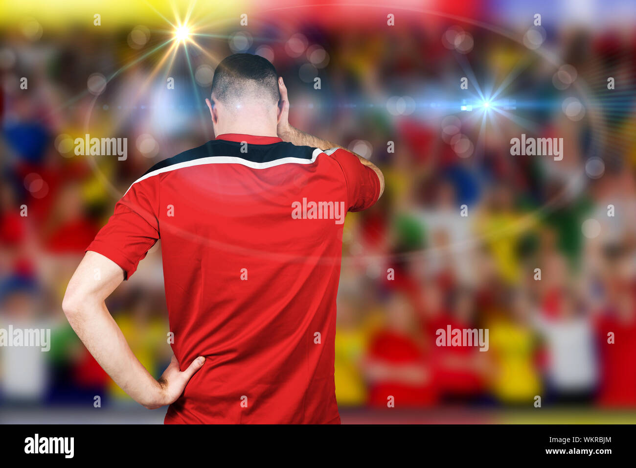 Disappointed football player looking down against blurry football pitch ...