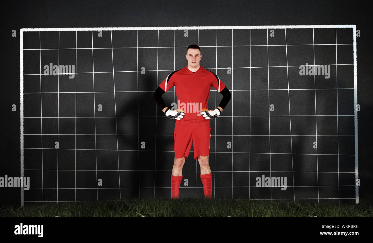 Composite image of goalkeeper in red looking at camera against goal net ...